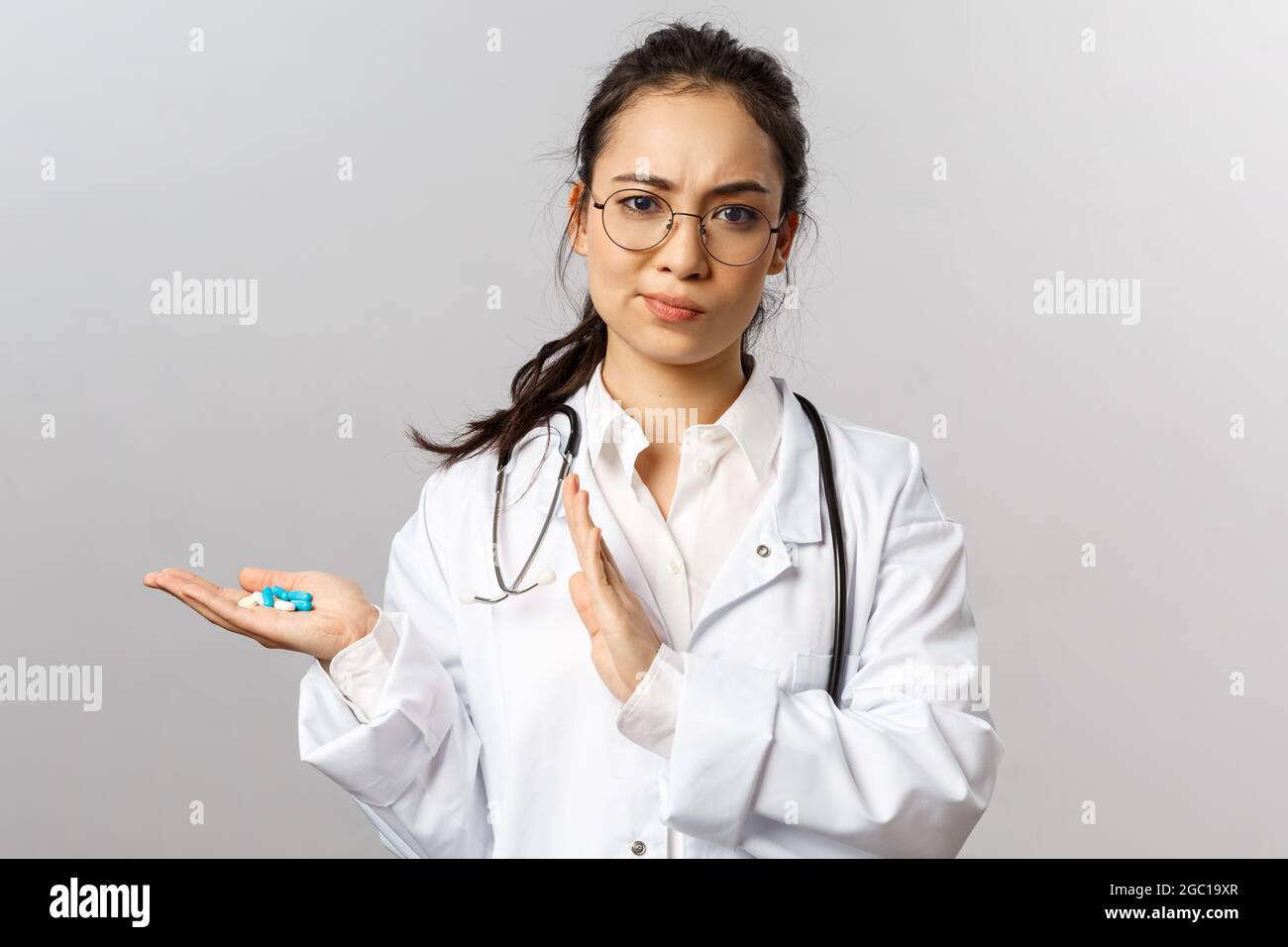 Portrait of displeased, serious-looking asian female doctor smirk ...