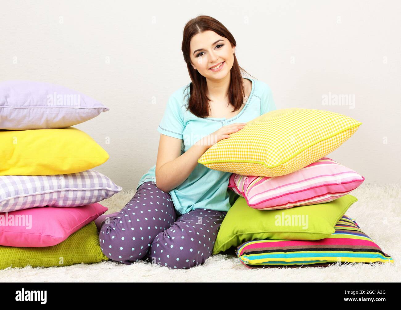 Beautiful young girl with pillows in room Stock Photo - Alamy