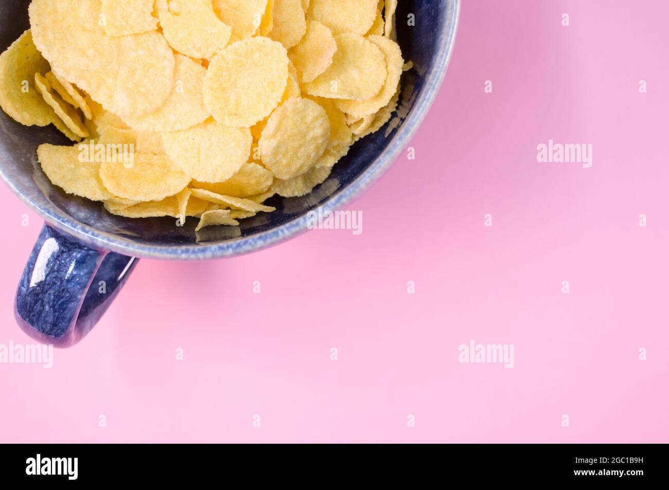 Top view of corn flakes on a cup isolated on light pink background ...