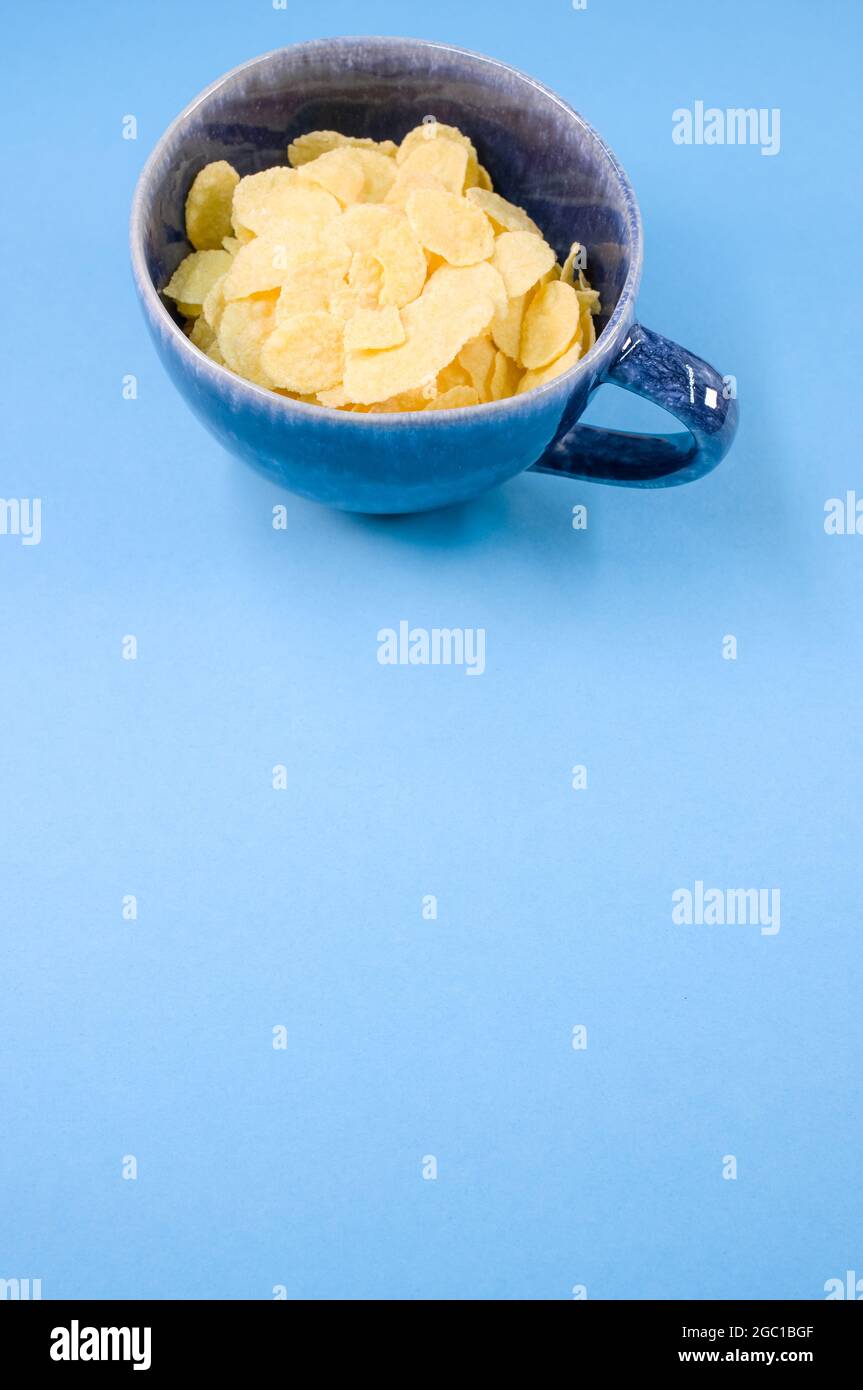 Vertical of corn flakes on a cup isolated on blue background Stock ...