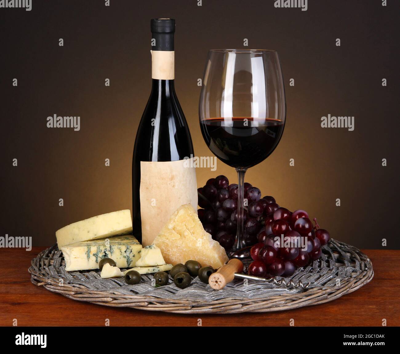 Refined still life of wine, cheese and grapes on wicker tray on wooden ...