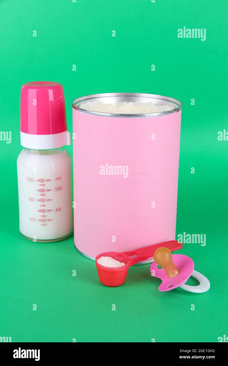 Powdered milk with baby bottle of milk and nipple on green background ...