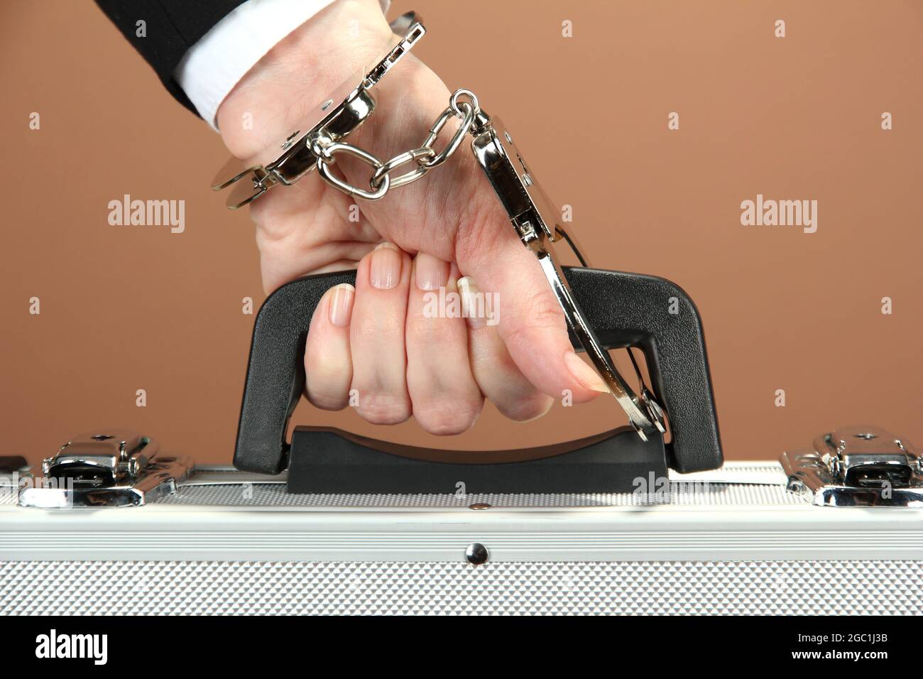 Hand with handcuff and suitcase, on color background Stock Photo - Alamy