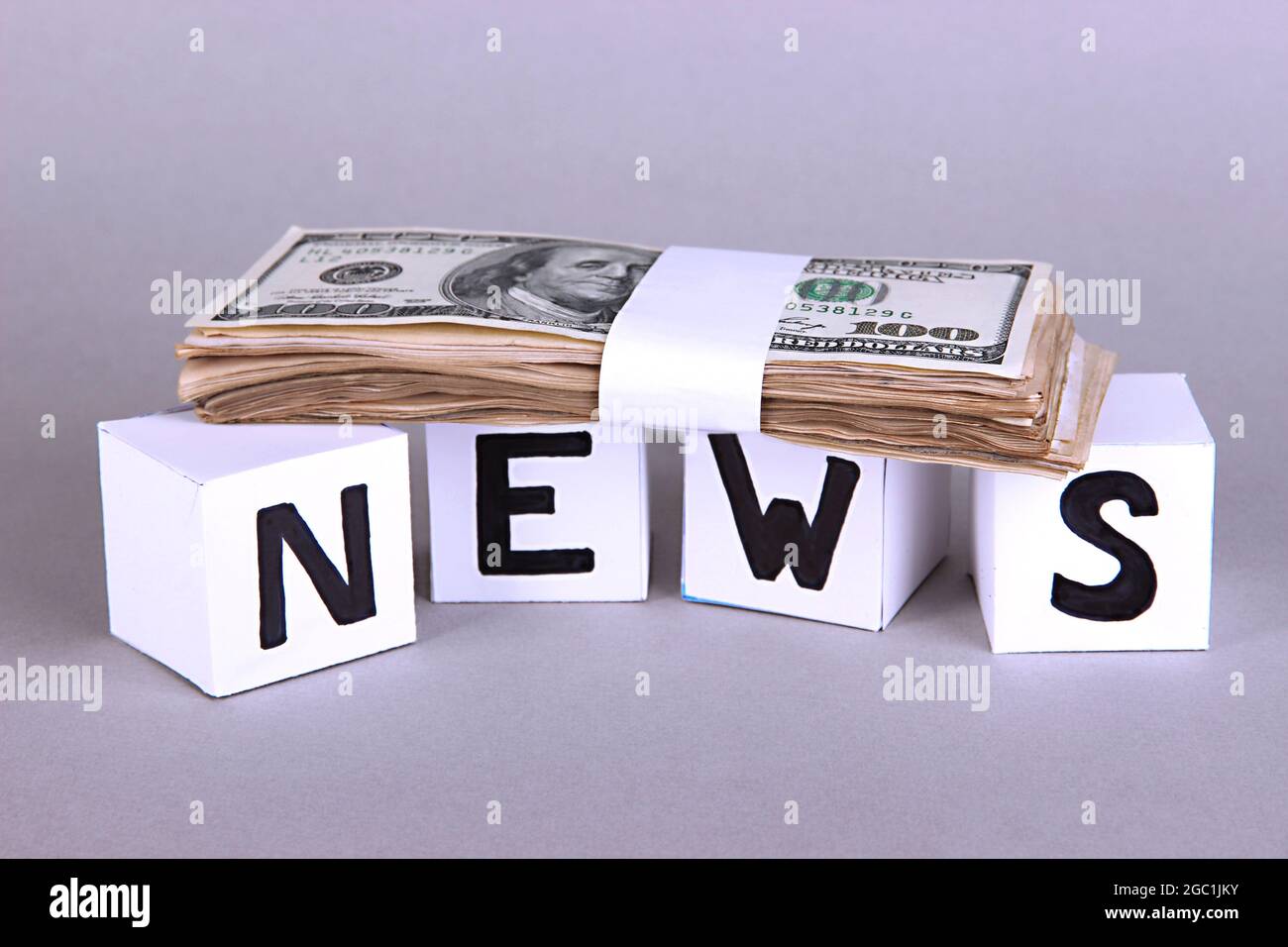White paper cubes labeled "News" with money on grey background Stock ...