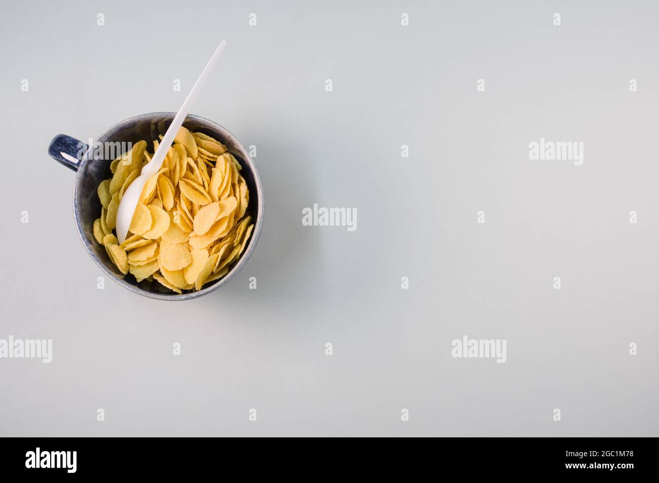 Top view of corn flakes on a cup with plastic spoon isolated on a light ...