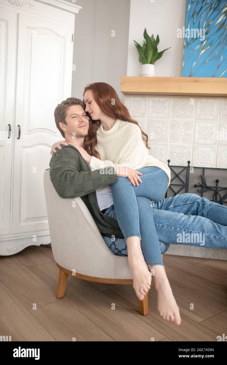 Woman hugging man sitting together in armchair Stock Photo - Alamy