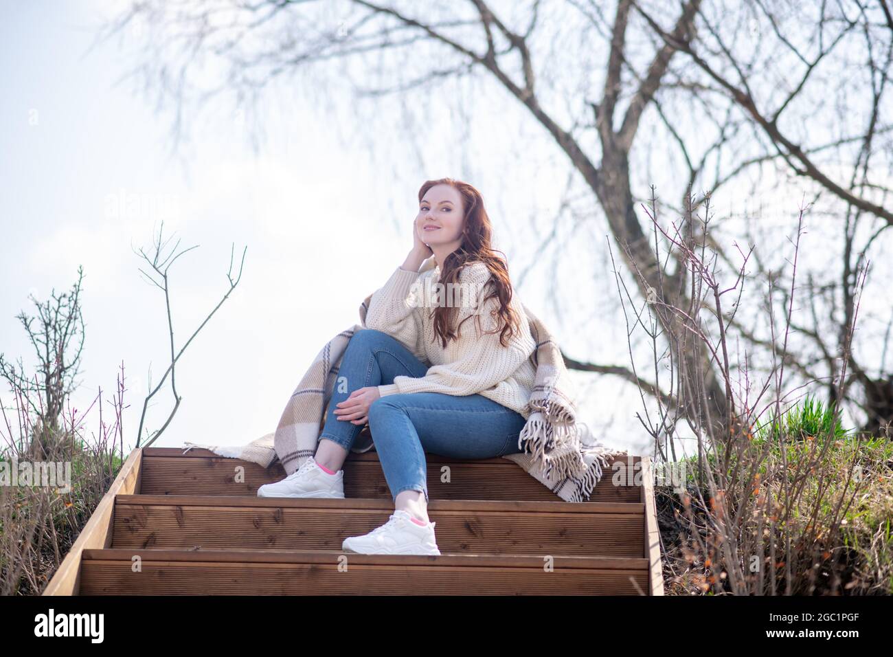 Smiling dreamy woman sitting on stairs in nature Stock Photo - Alamy