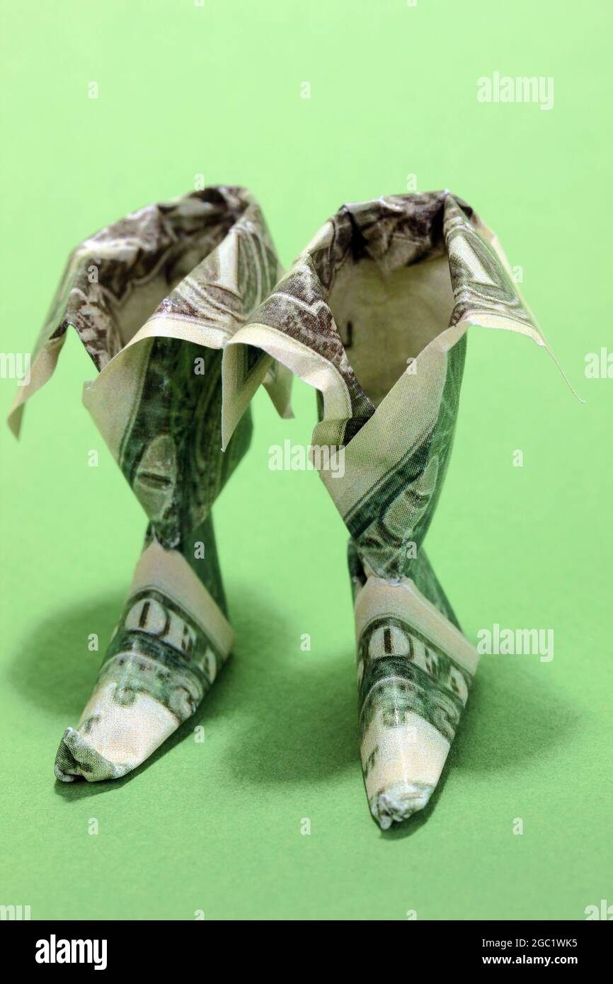 Dollar folded into boots on green background Stock Photo - Alamy