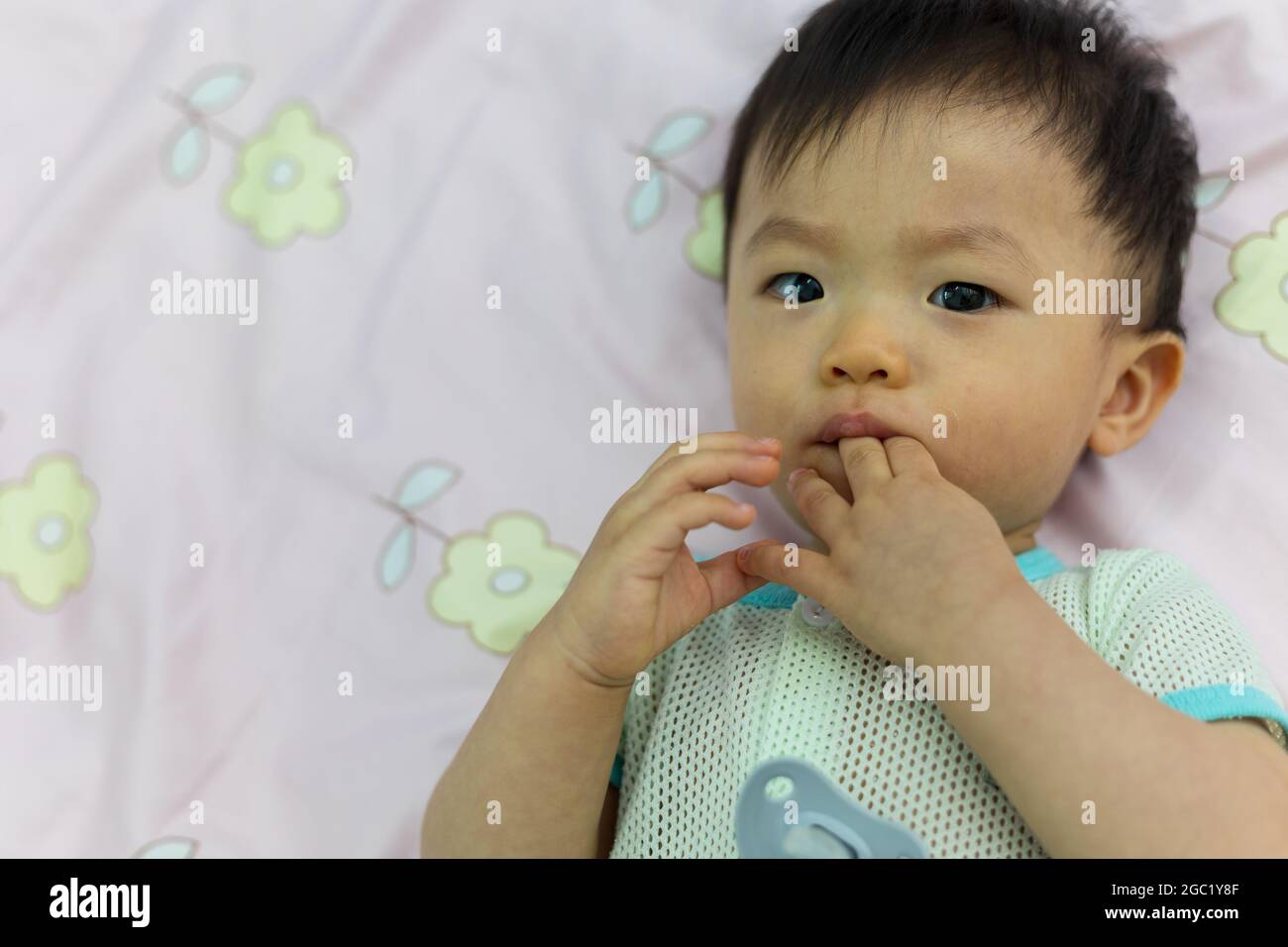 Portrait Adorable and happy Chinese baby boy child relaxing in bed ...