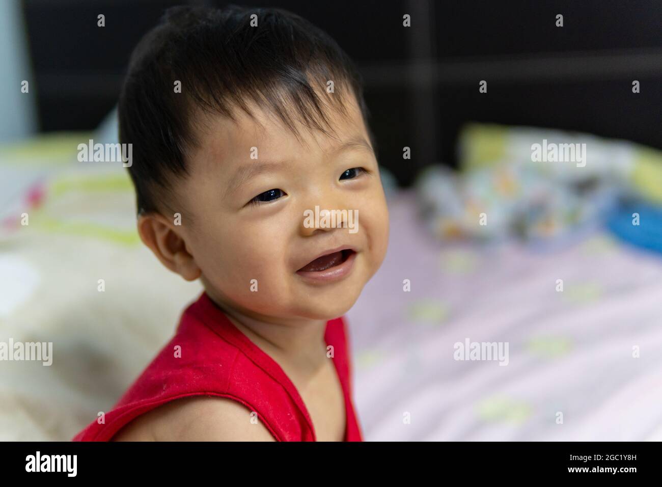 Portrait Adorable and happy Chinese baby boy child relaxing in bed ...