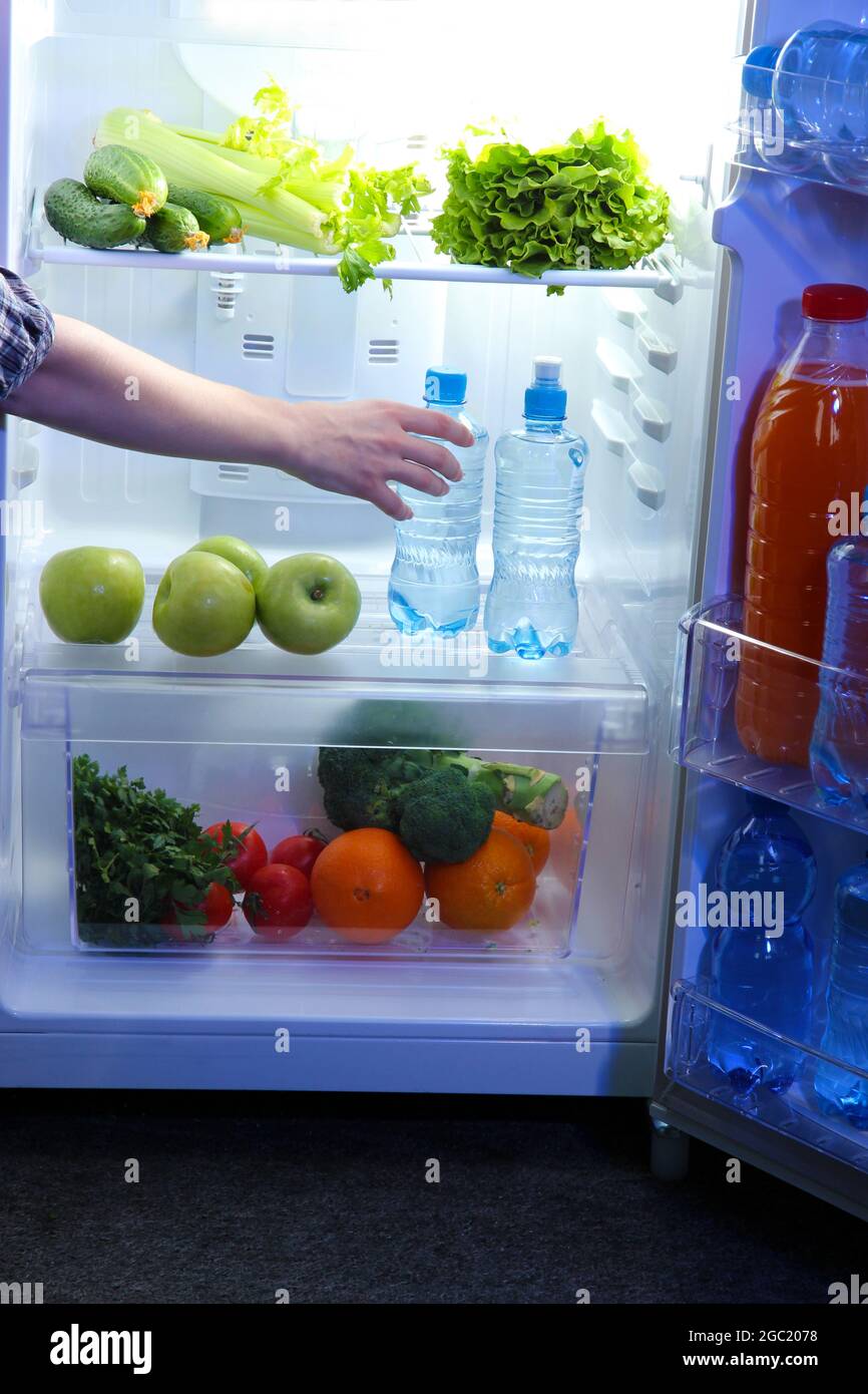 Woman's hand reaching out for food from the refrigerator, close up ...