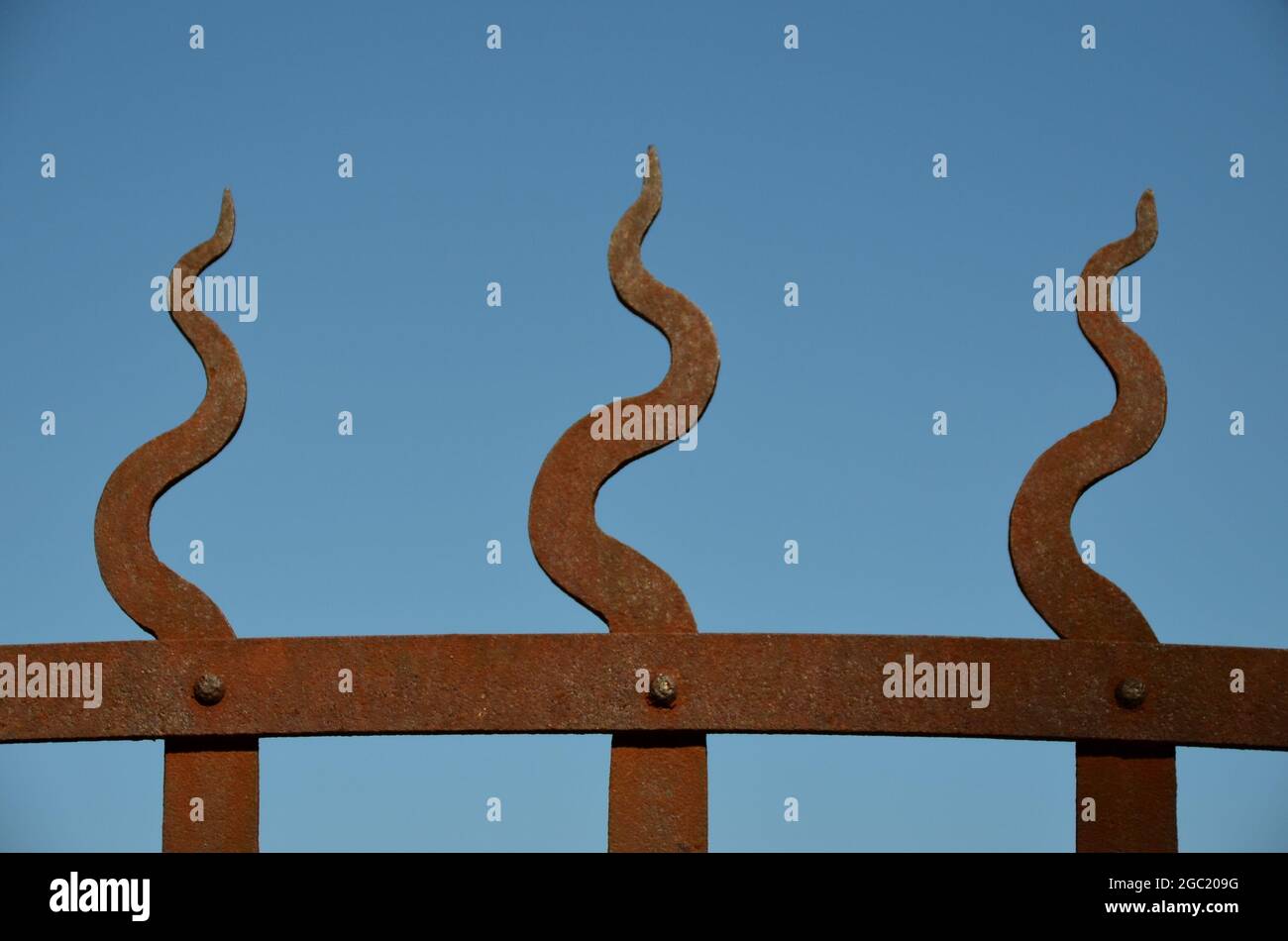 Wavy old wrought iron fence tips under the blue sky Stock Photo - Alamy