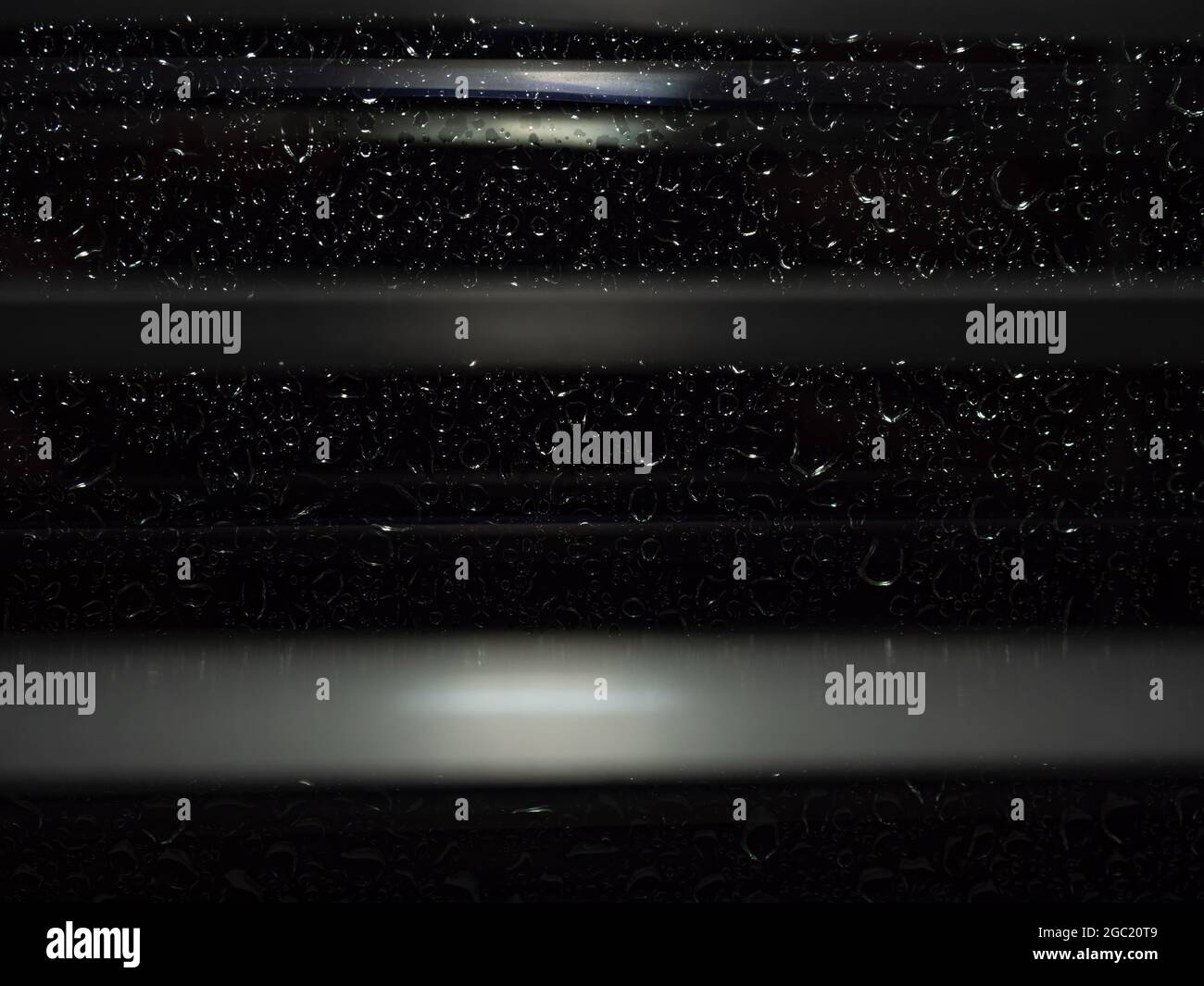 Shining raindrops on a window glass in the night through the window ...