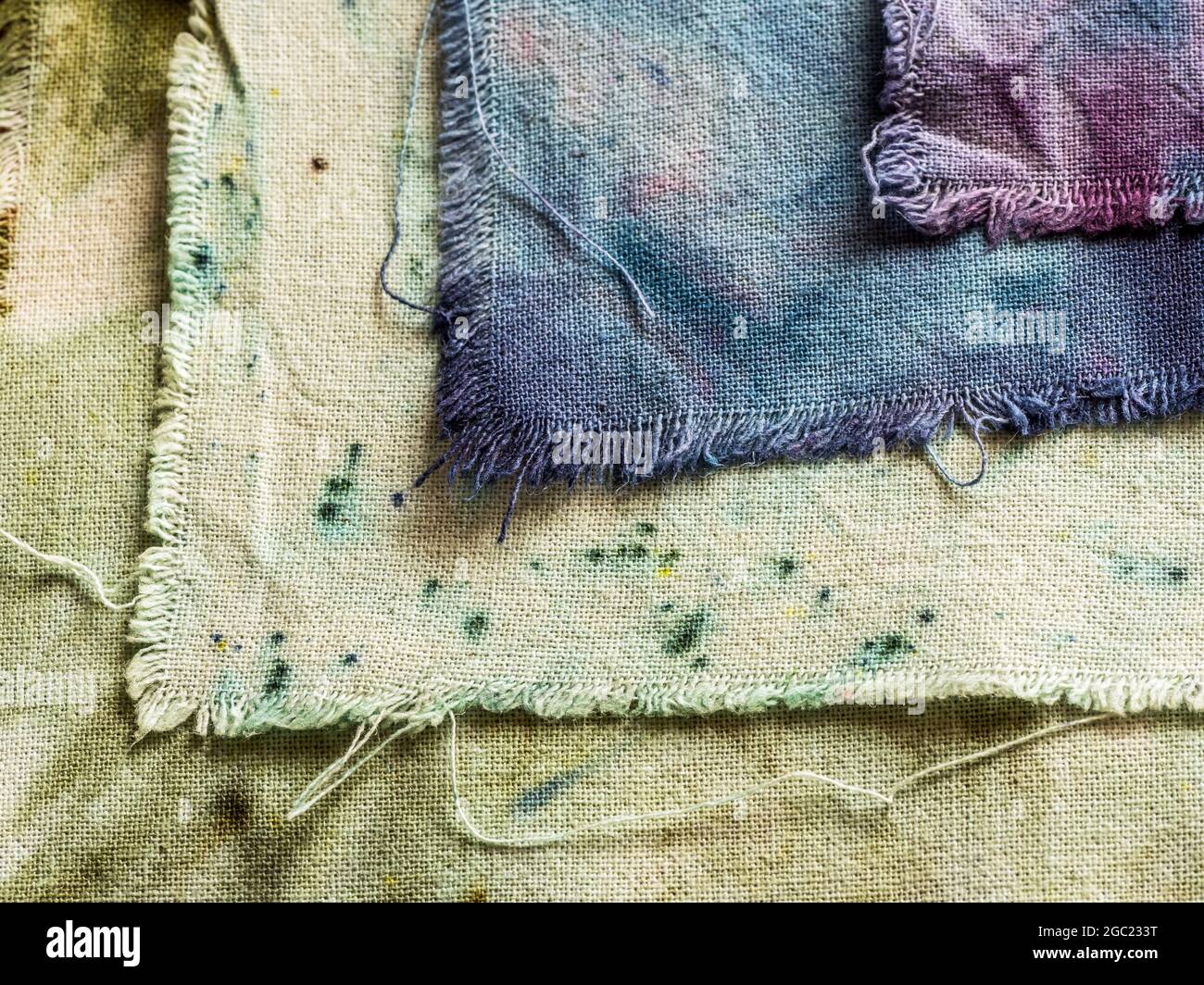 Closeup of overlapping colorful hand-dyed wet cotton fabrics shot from ...
