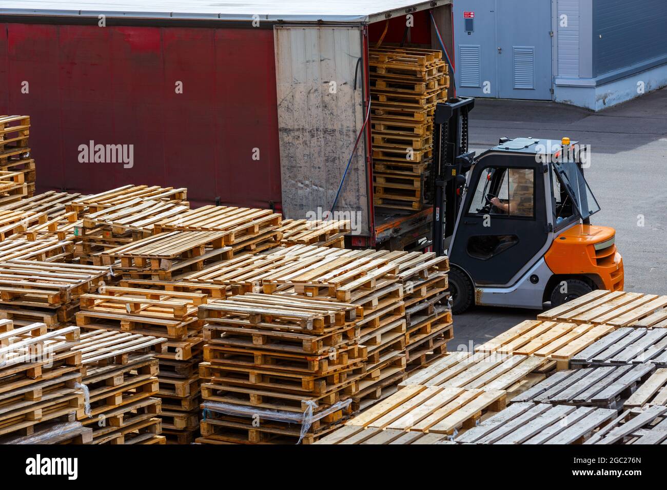 forklift loading used wooden pallet stacks into truck - perspective ...