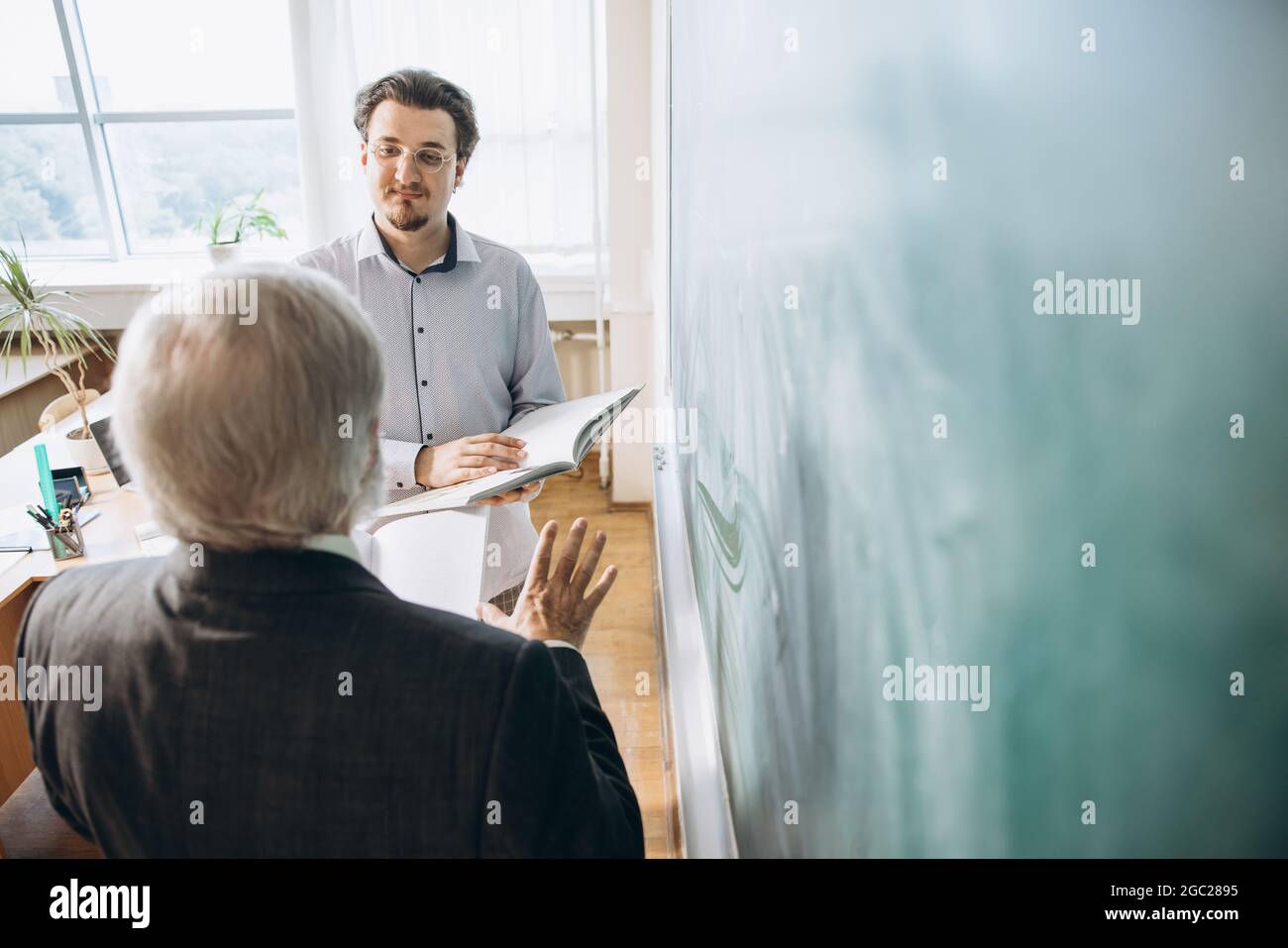Elderly gray-headed man, professor, teacher and students at lecture ...