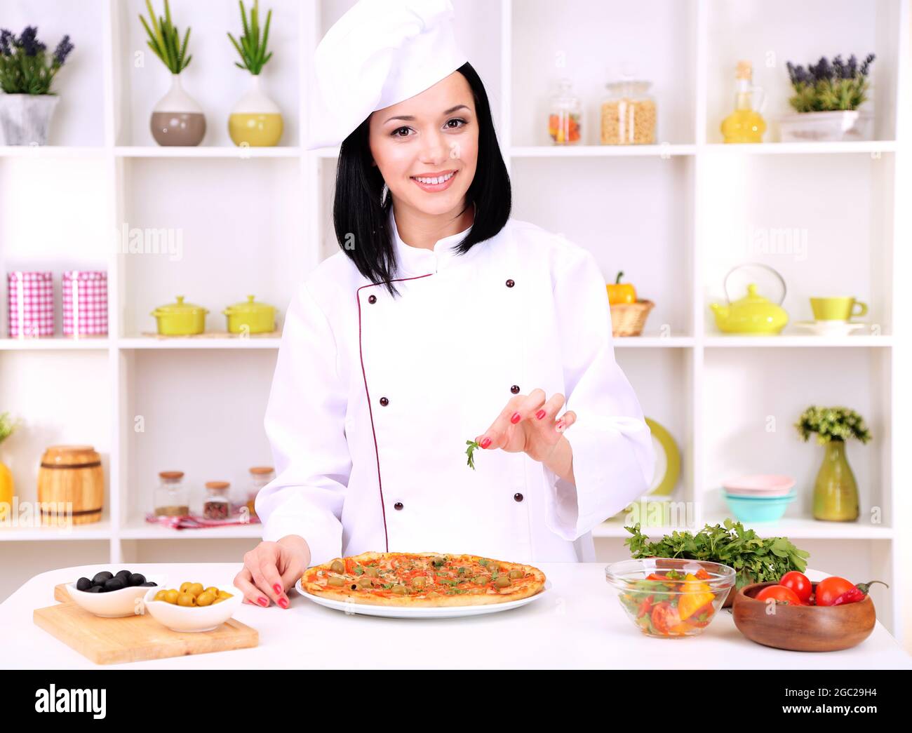 Beautiful girl chief-cooker with pizza on kitchen background Stock ...