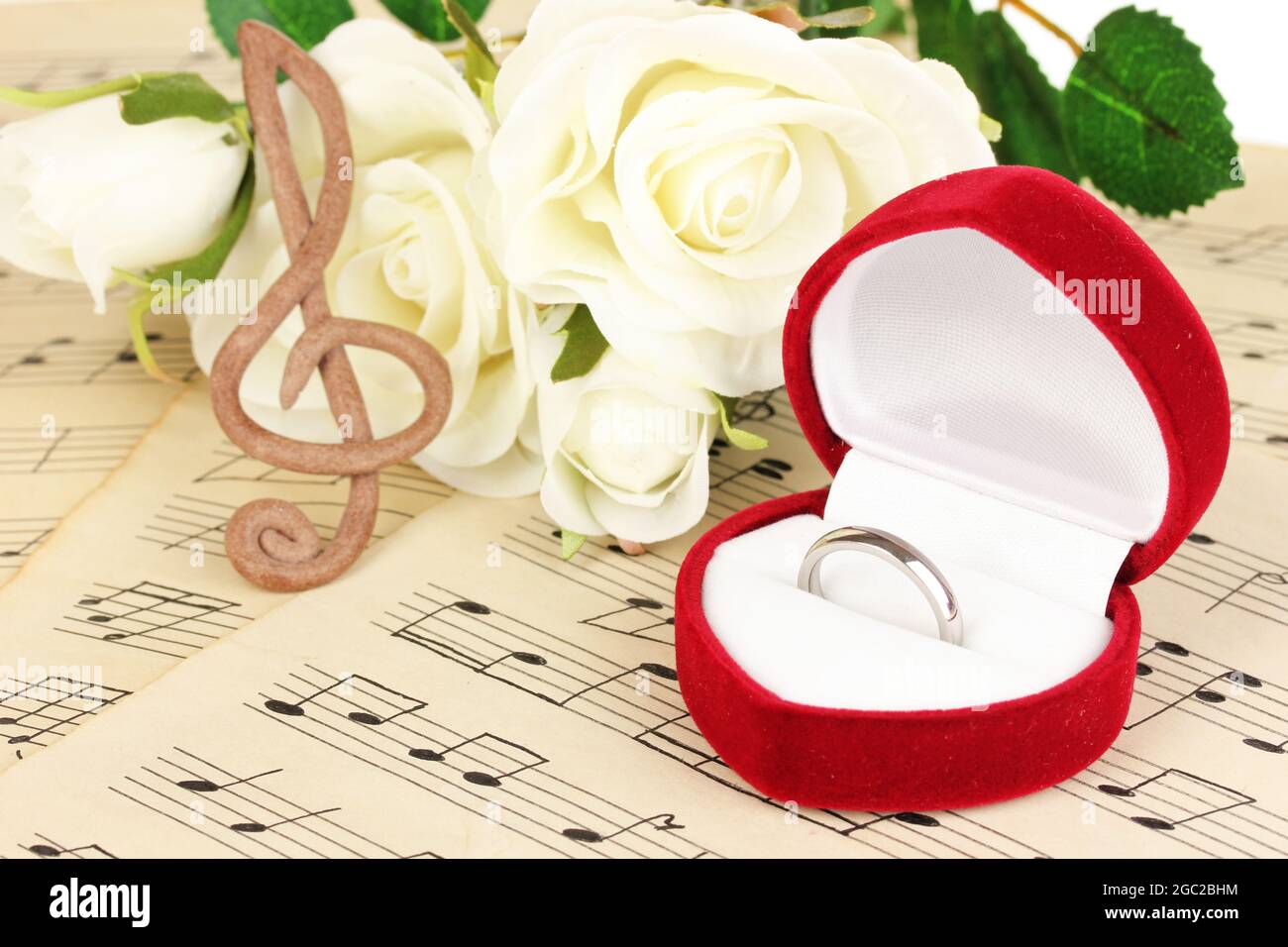 Treble clef, roses and box holding wedding ring on musical background ...