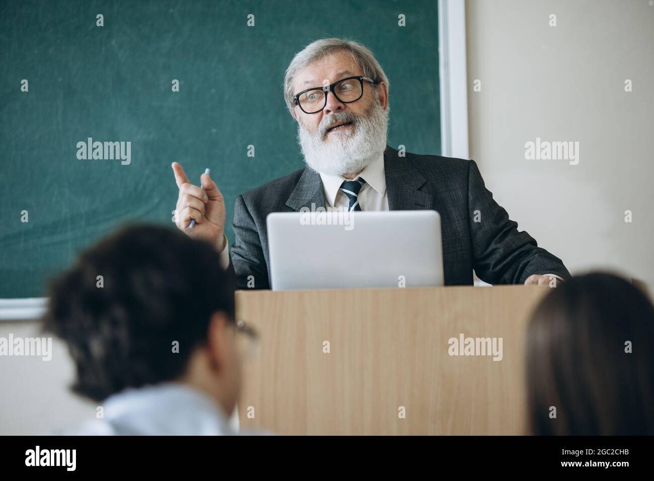 Elderly gray-headed man, professor, teacher and students at lecture ...