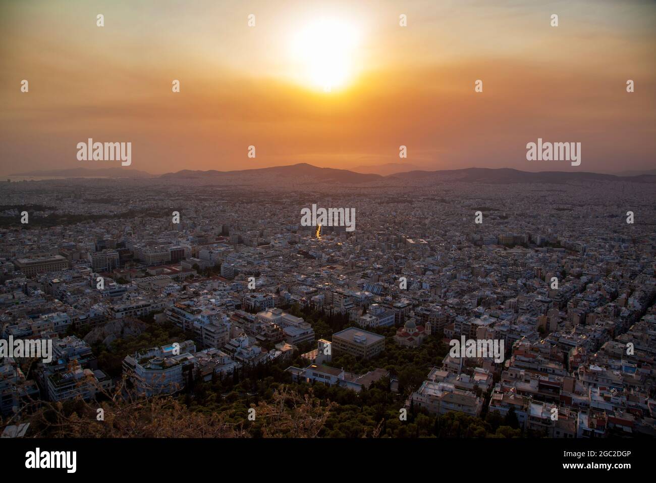 Sunset in Athens, Greece. The city is covered by smoke cloud due to the ...
