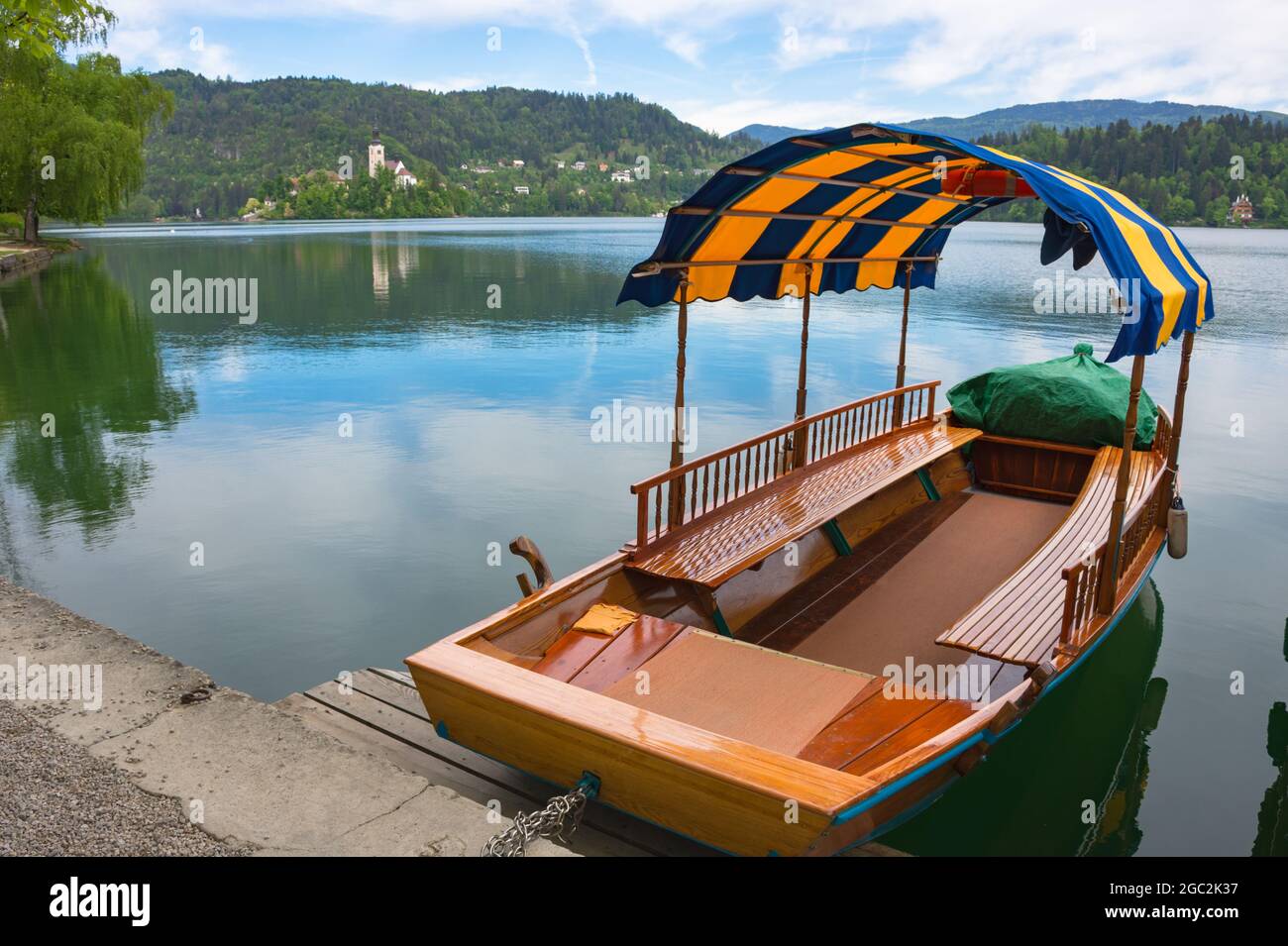 Traditional Pletna boat waiting for tourists on Lake Bled, with the ...