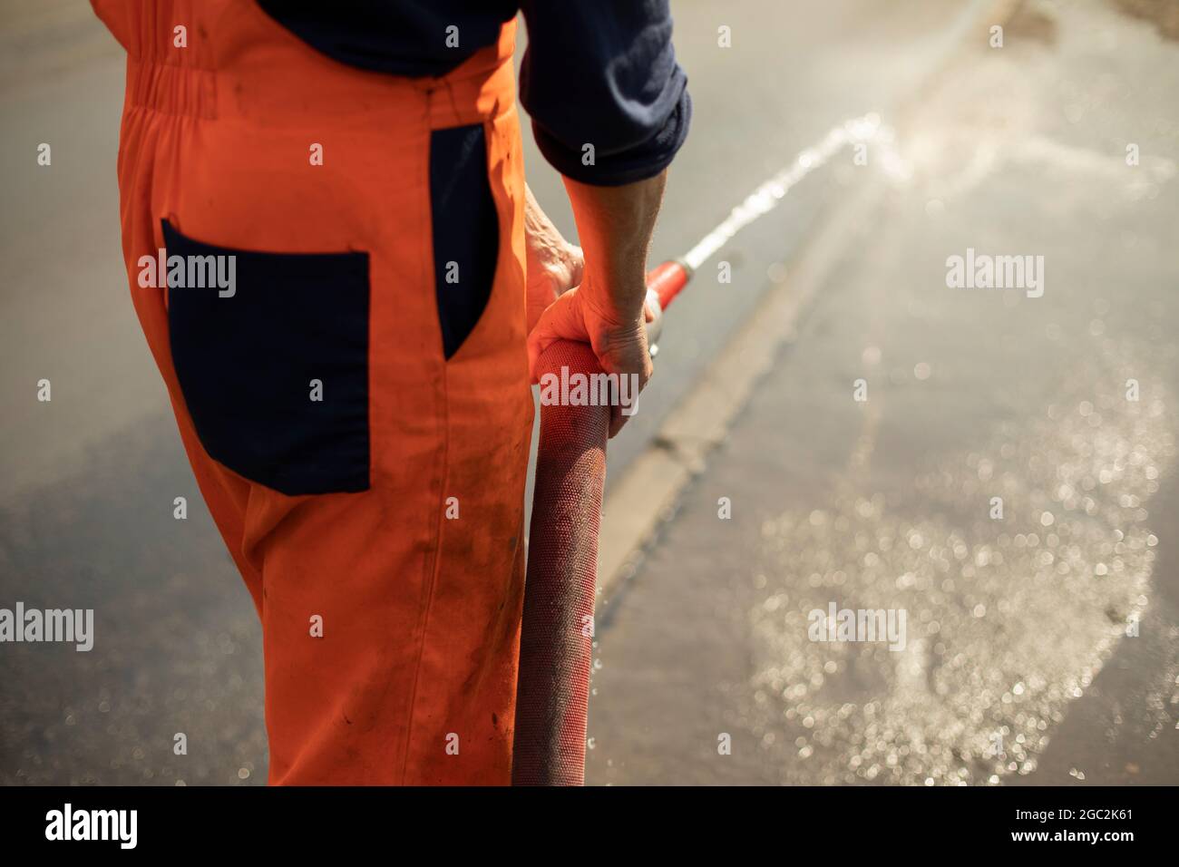 Water hose. The flow of water from the pipe. A man holds a fire hose ...