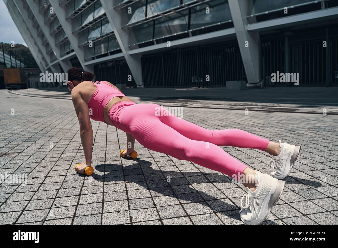 Behind view of female doing push-ups using dumbbells Stock Photo - Alamy