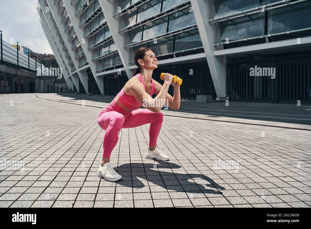 Adult doing squat exercise on empty street Stock Photo - Alamy