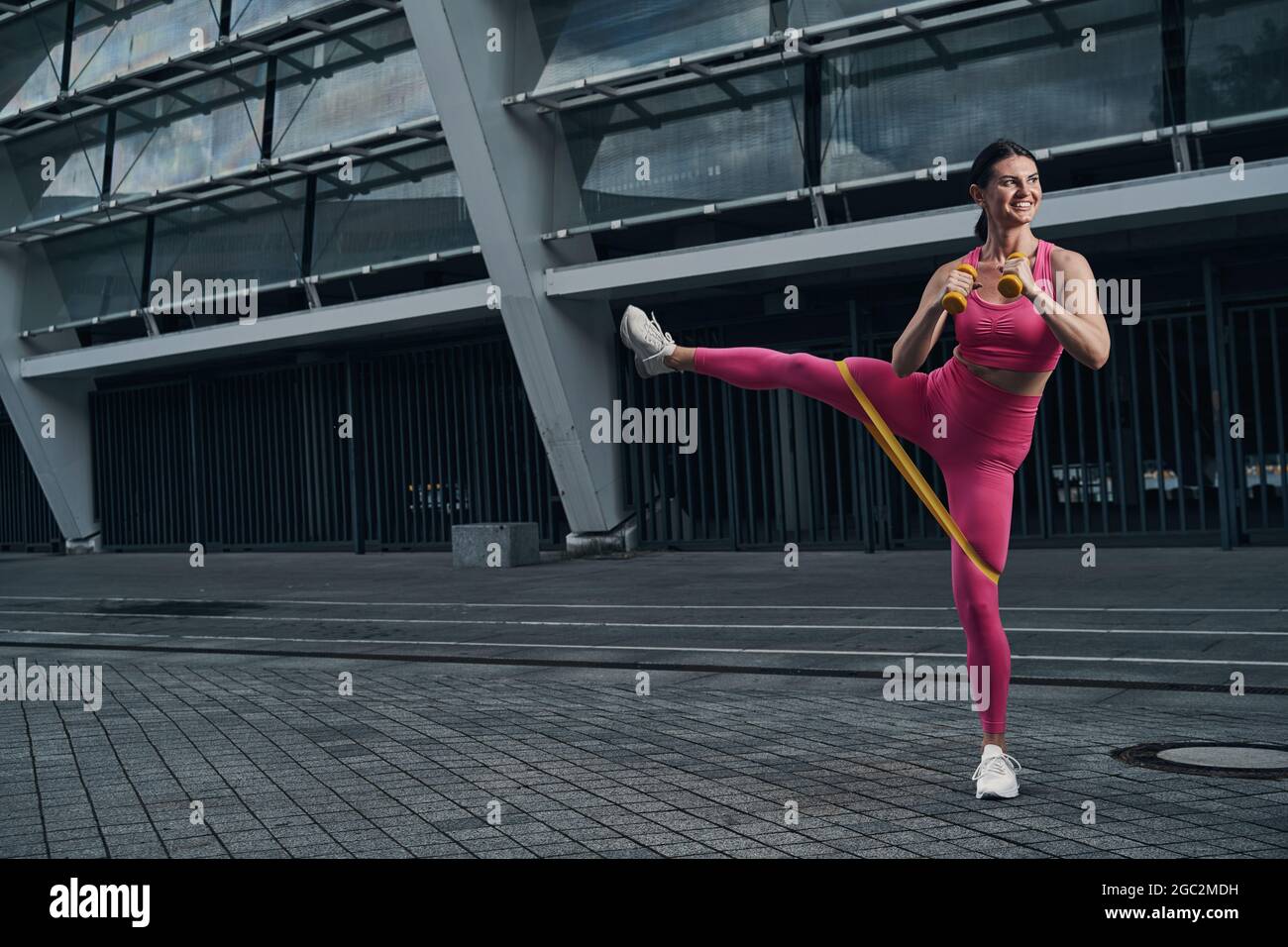 Female with dumbbels lifting right leg outdoors Stock Photo - Alamy
