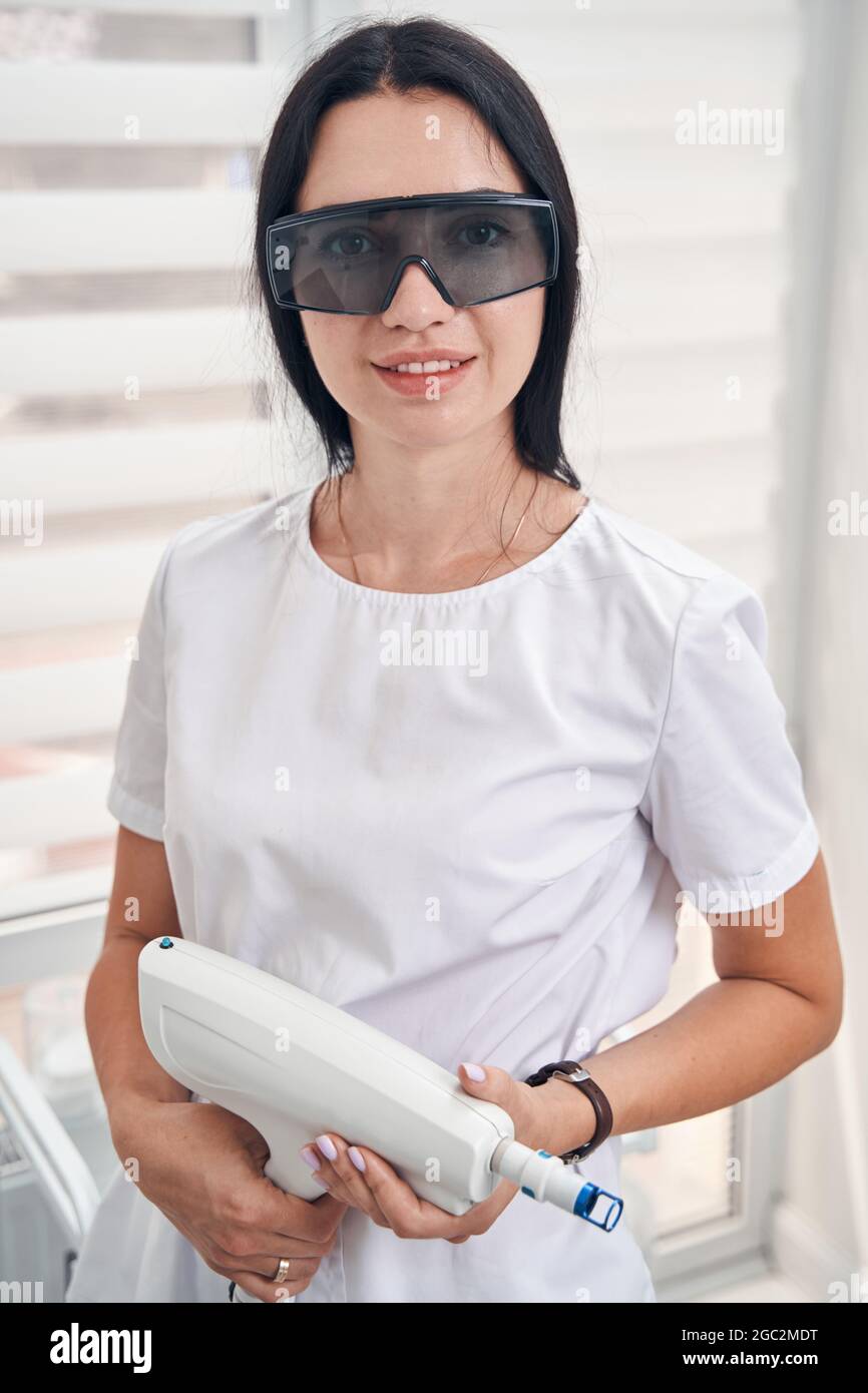 Cheerful young woman doing laser treatment in clinic Stock Photo - Alamy