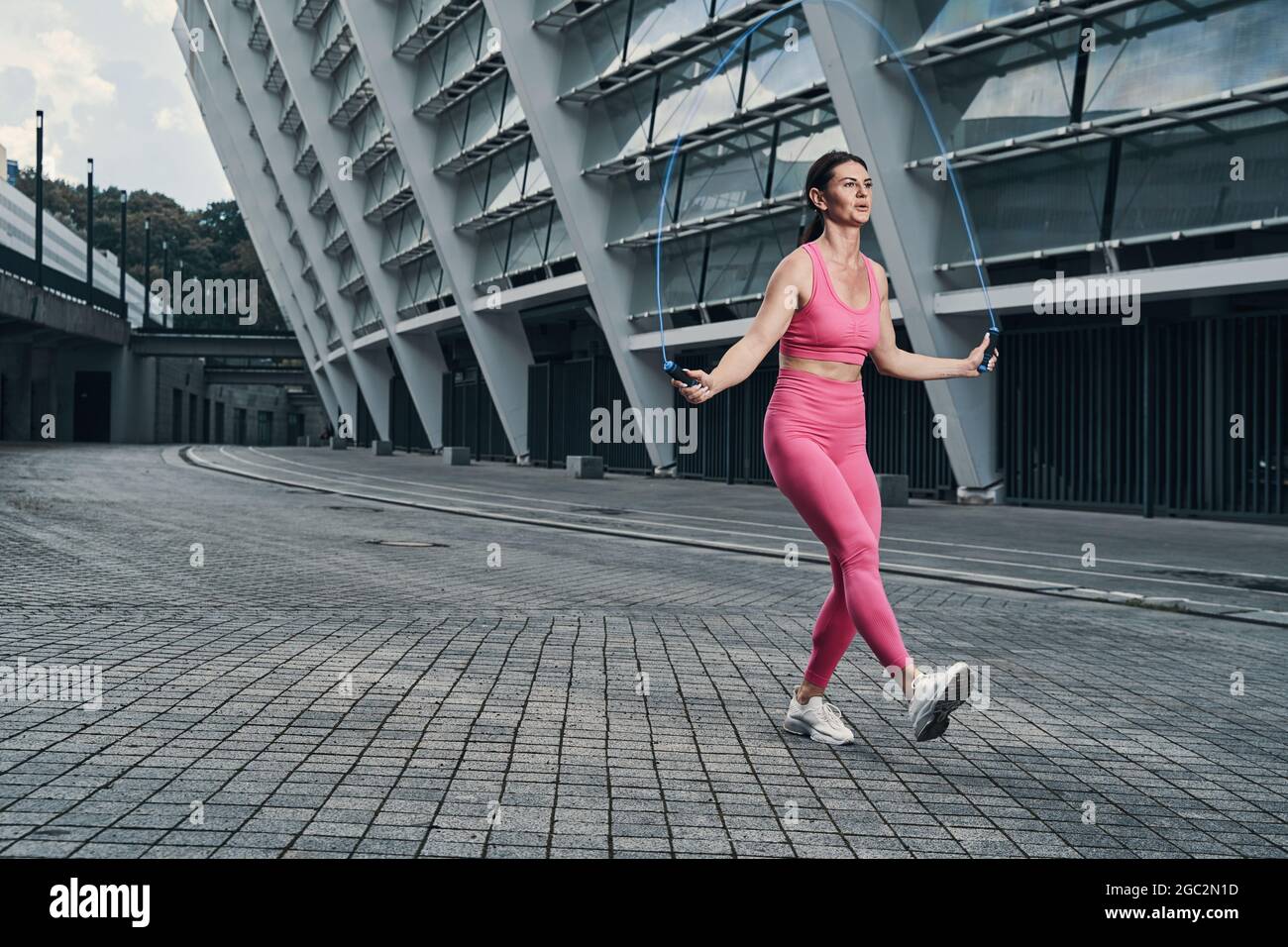 Female athlete using skipping rope during training on street Stock ...