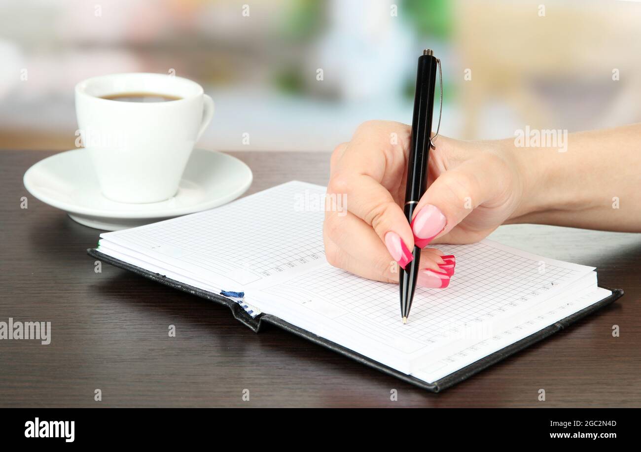 Hand signing in notebook, on bright background Stock Photo - Alamy