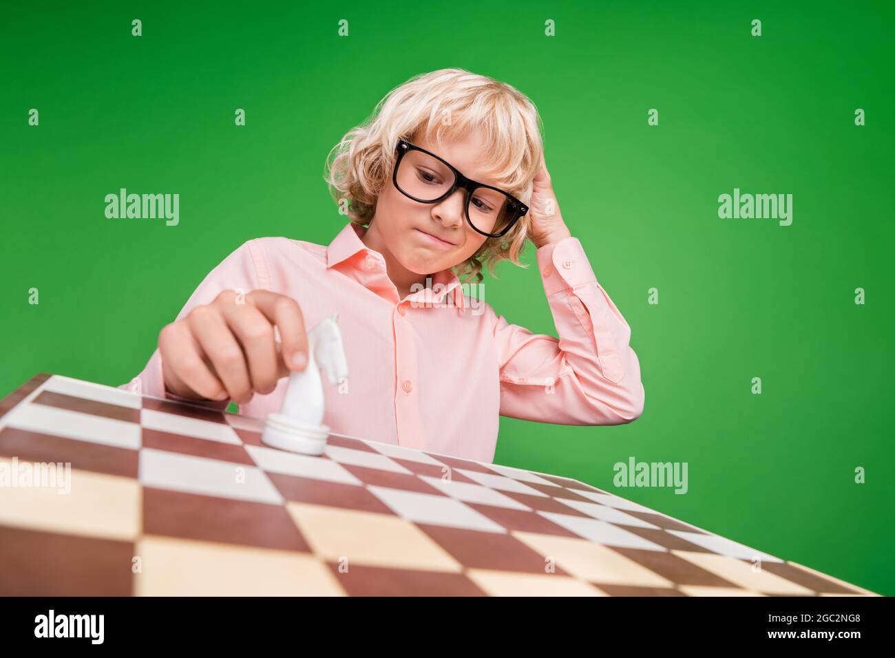 Photo of young puzzled minded boy look board think move chess horse ...