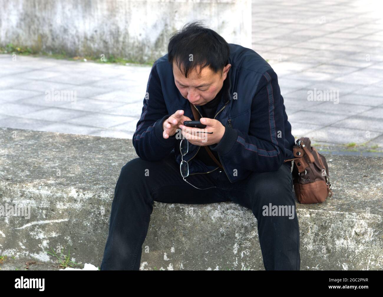 A Man Checking His Mobile Phone By The Side of the Road in Greenwich ...