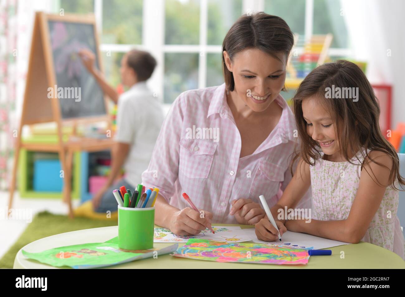 Cute girl with mother drawing at home Stock Photo - Alamy