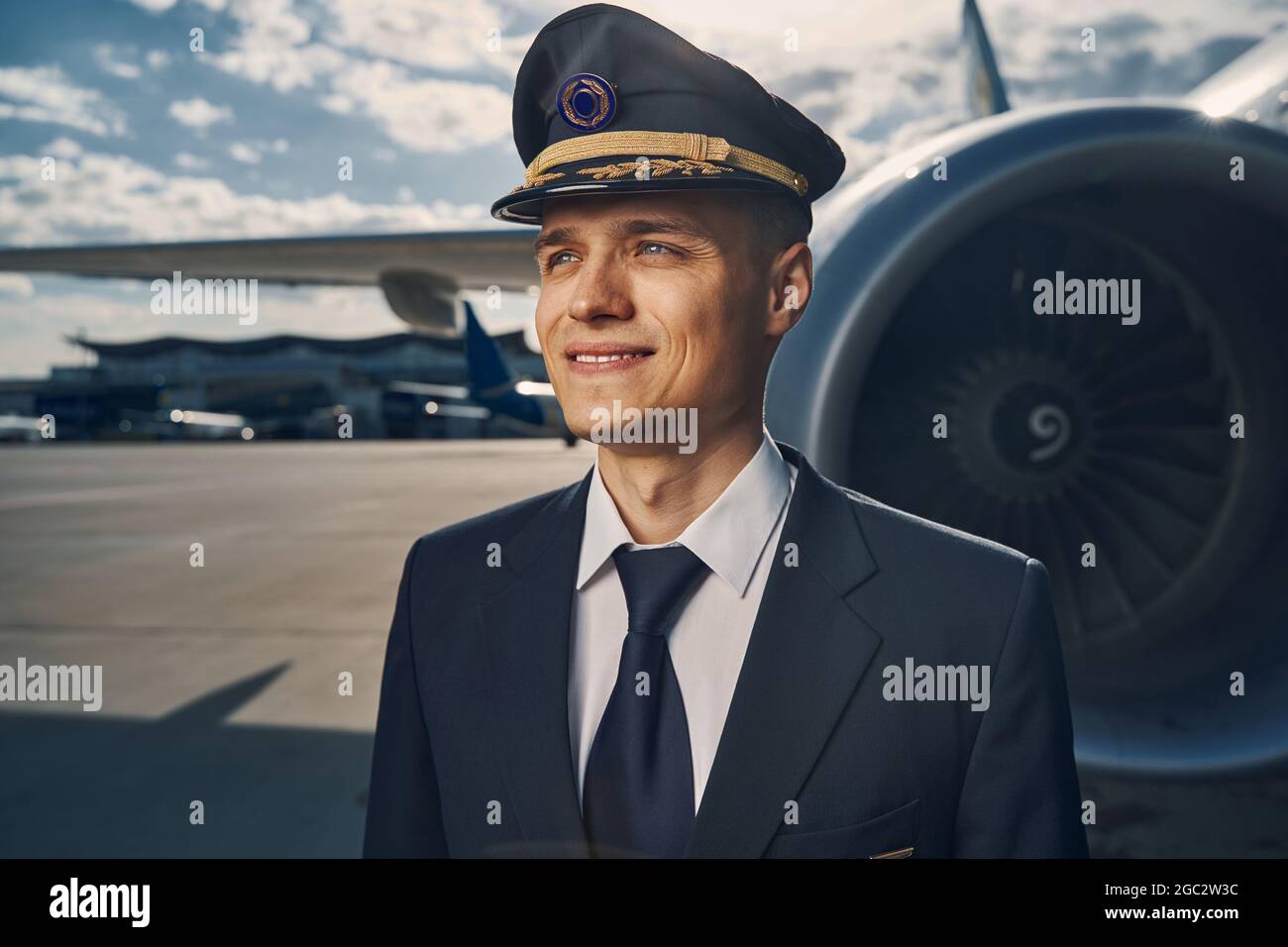 Smiling airline pilot in a cap gazing into the distance Stock Photo - Alamy