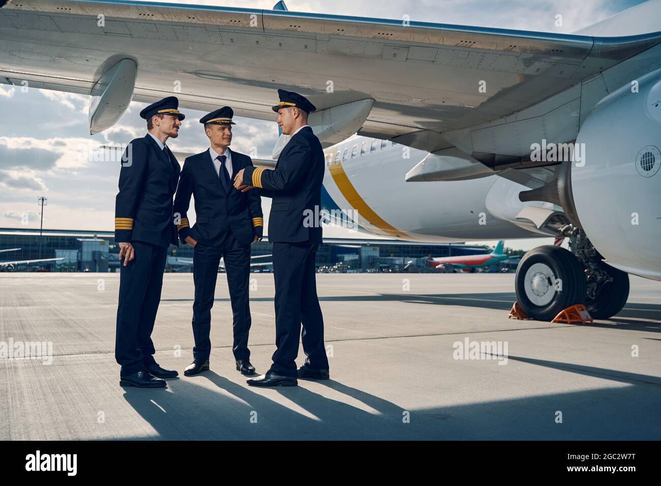 Three aviators having a conversation by a landed plane Stock Photo - Alamy