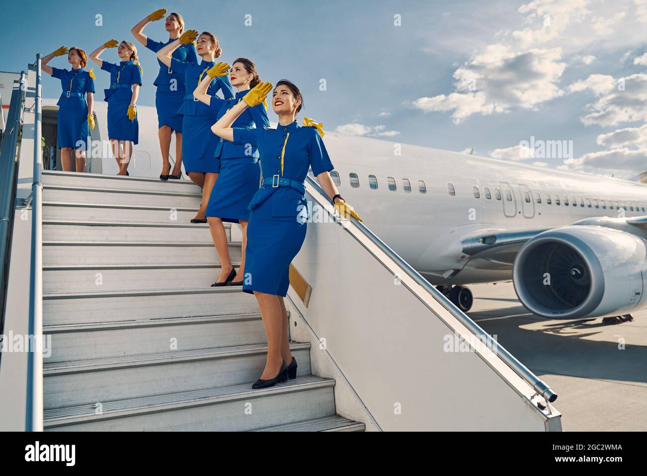Six slim beautiful stewardesses saluting on the aircraft steps Stock ...