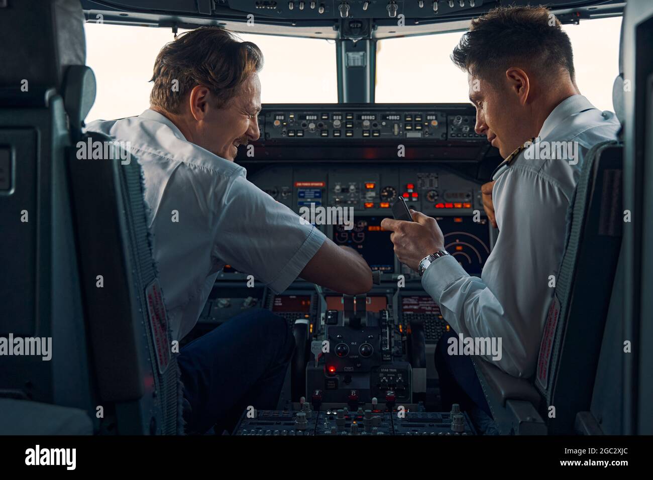 Cheerful pilot and a co-pilot seated in the flight deck Stock Photo - Alamy