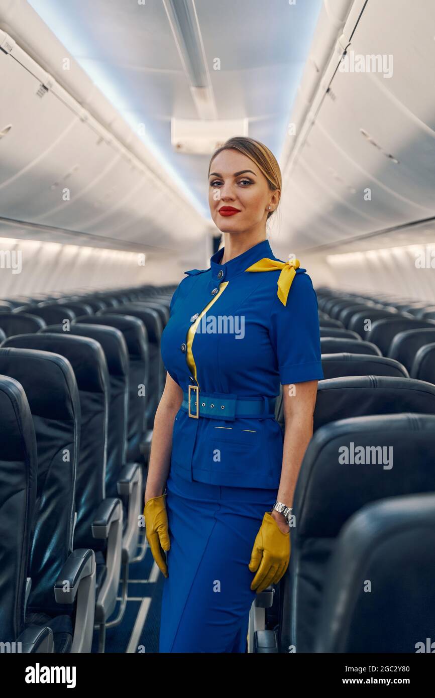 Beautiful tranquil stewardess posing for the camera aboard the plane ...