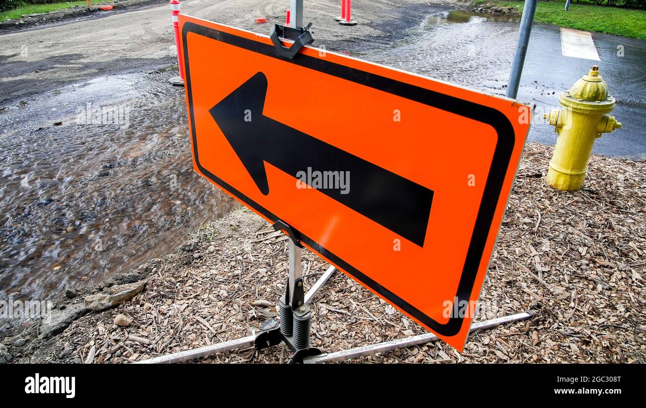 Street view with leaking water from water pipe and large orange sign ...