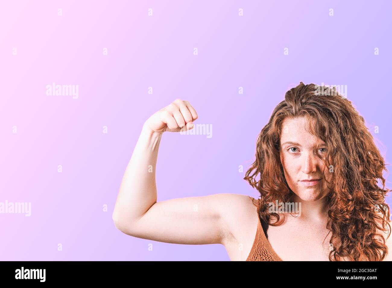 Young ginger female posing showing off her muscles on a purple ...