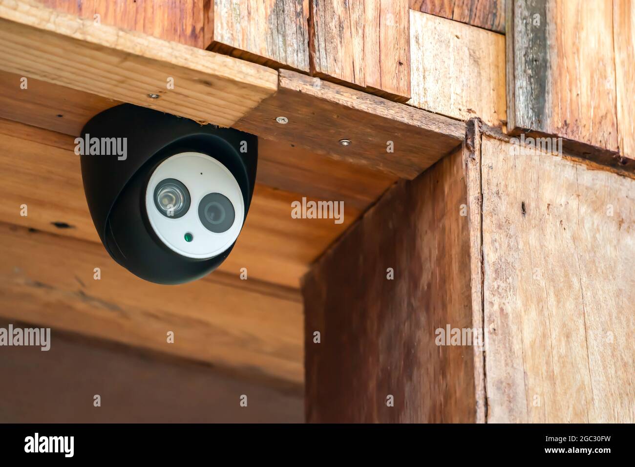 close up mini CCTV camera black case is set up on the wood ceiling ...