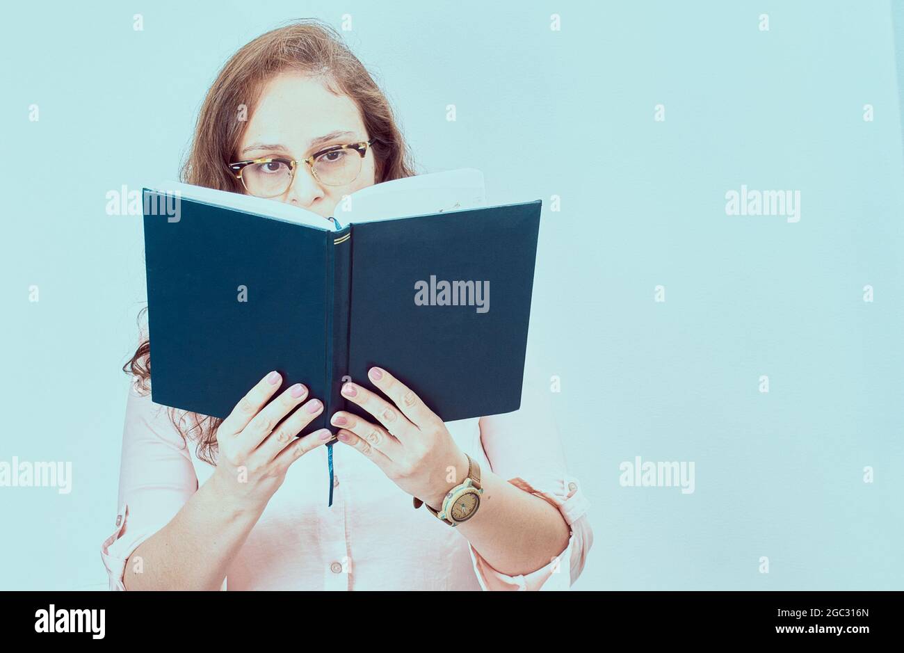 Girl reading a book standing near the light blue wall Stock Photo - Alamy