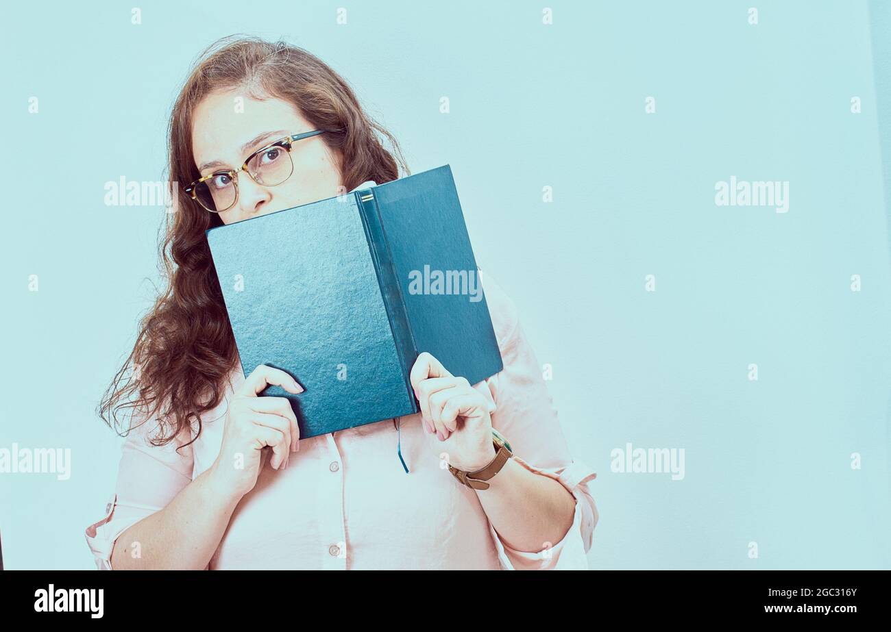 Girl reading a book standing near the light blue wall Stock Photo - Alamy