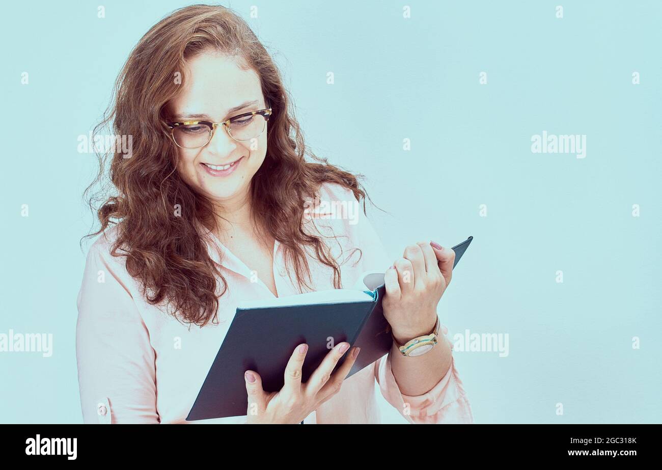 Girl reading a book standing near the light blue wall Stock Photo - Alamy