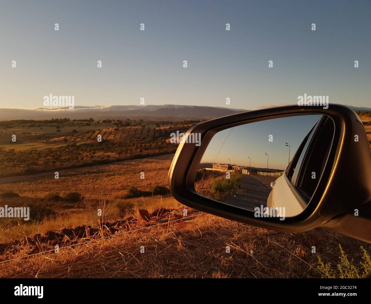 Closeup shot of a car wing mirror in a deserted countryside at sunset ...