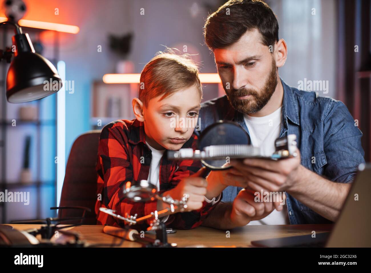 Bearded man and little boy using magnifying glass for examining problem ...