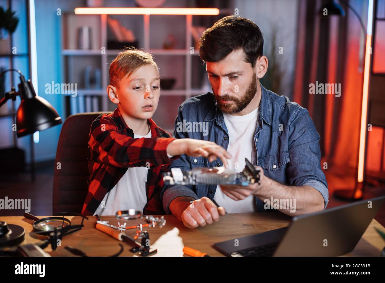Focused little boy and handsome man repairing display card from modern ...