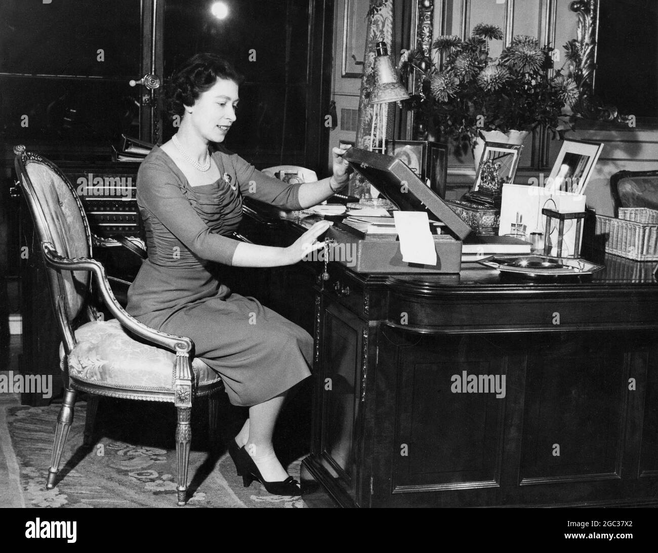 HM Queen Elizabeth II at her desk in Buckingham Palace as she opens one ...